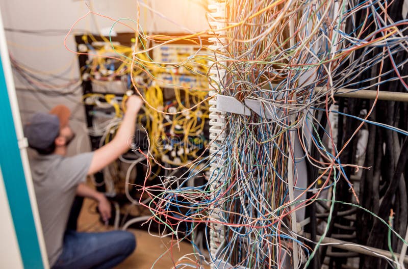 Network Engineer Working in Server Room. Connecting Network Cables To ...