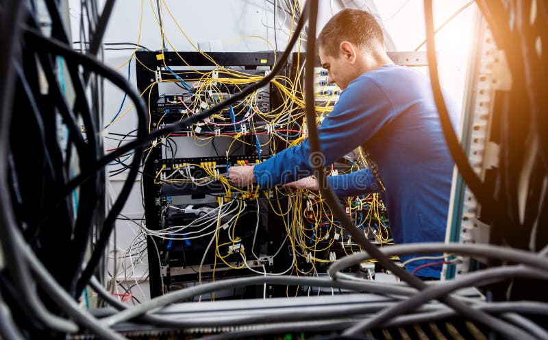 Network Engineer Working in Server Room. Connecting Network Cables To ...