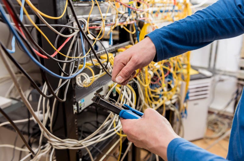Network Engineer Working in Server Room. Connecting Network Cables To ...