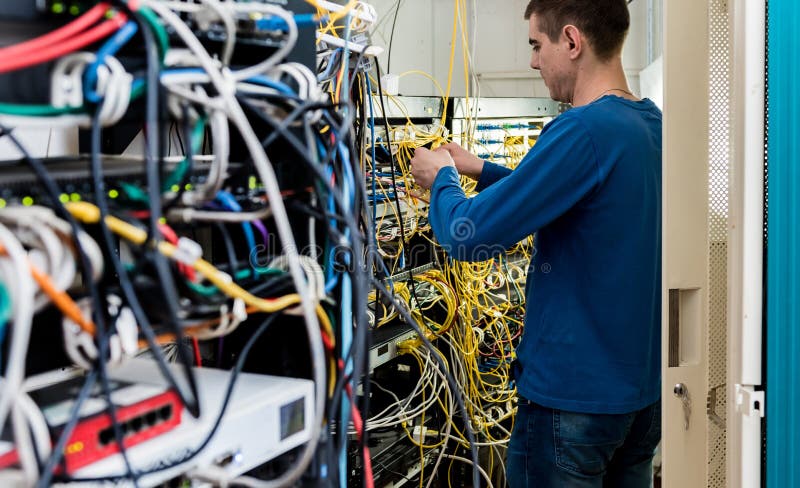 Network Engineer Working in Server Room. Connecting Network Cables To ...