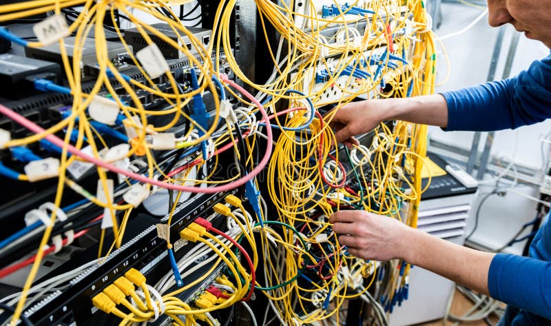 Network Engineer Working in Server Room. Connecting Network Cables To ...