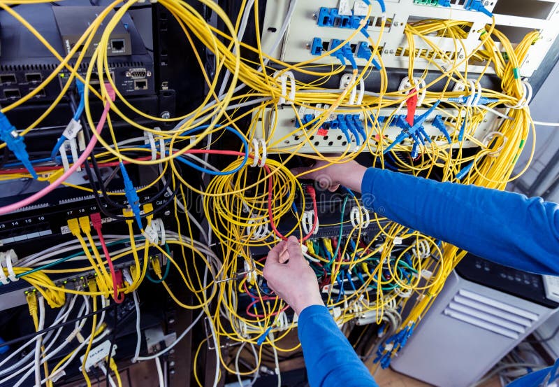 Network Engineer Working in Server Room. Connecting Network Cables To ...