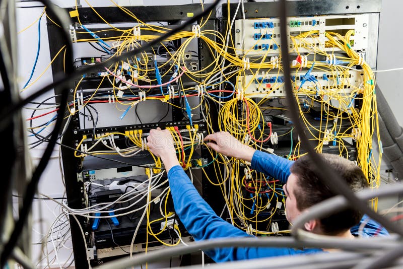 Network Engineer Working in Server Room. Connecting Network Cables To ...