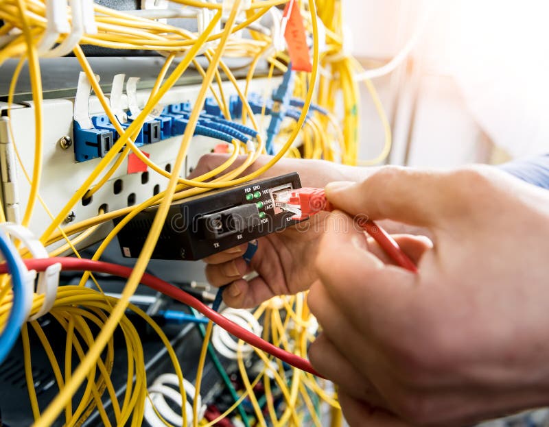 Network Engineer Working in Server Room. Connecting Network Cables To ...