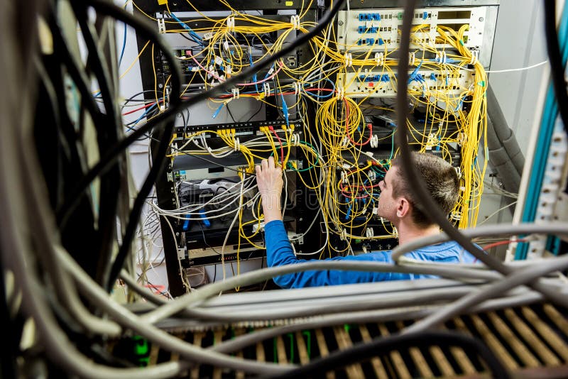 Network Engineer Working in Server Room. Connecting Network Cables To ...