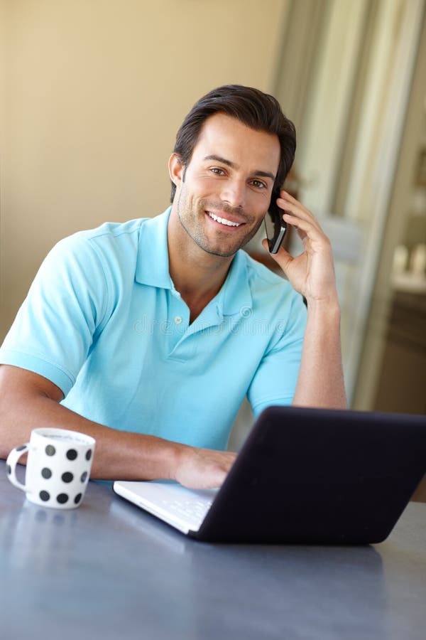 Networking from Home. a Handsome Man Talking on the Phone while Using ...