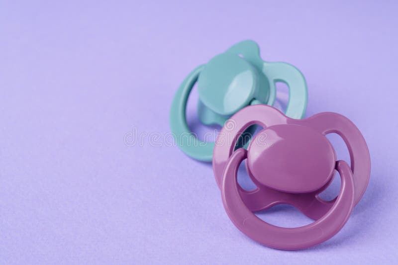 New Baby Pacifiers on Purple Background, Closeup. Space for Text Stock ...