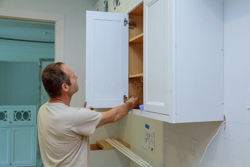In a New Home, a Carpenter is Fixing a Door To a Kitchen Cabinet Stock ...