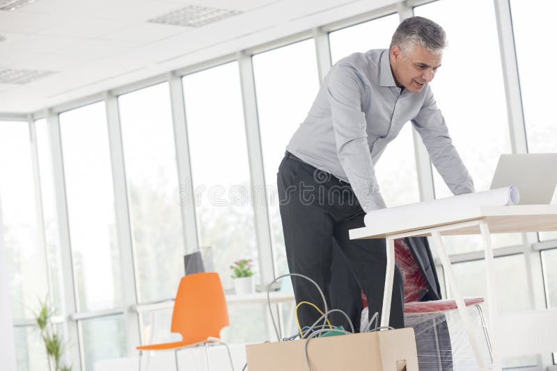 Mature Businessman Using Laptop while Leaning on Desk at New Office ...