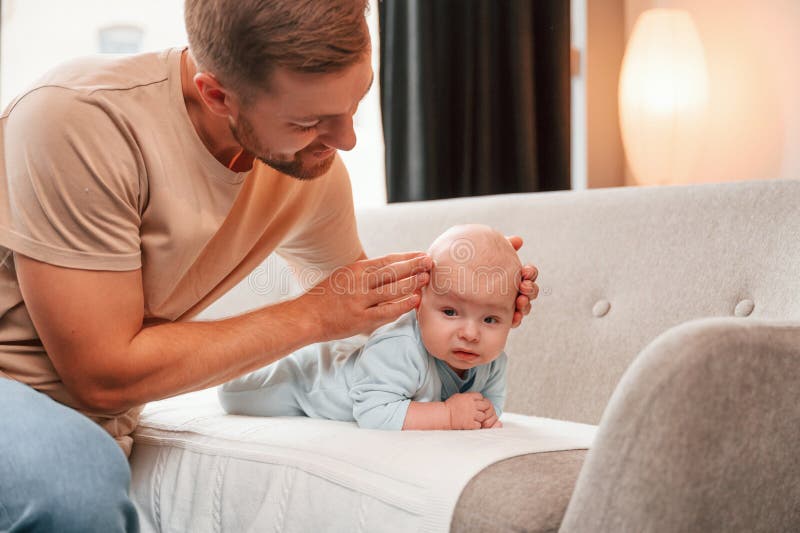Newborn Baby is Laying Down on the Sofa. Man is Indoors Stock Image ...
