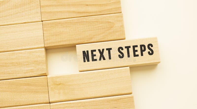 NEXT STEPS Text on a Strip of Wood Lying on a White Table Stock Image ...