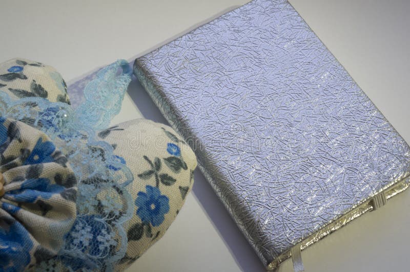 Next To the Notebook with a Silver Cover is a Printed Decorative Pad ...