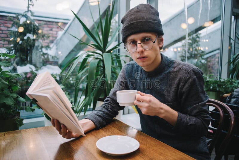 Nice Guy Hipster Glasses and Hat Reading a Book and Drinking Tea in ...