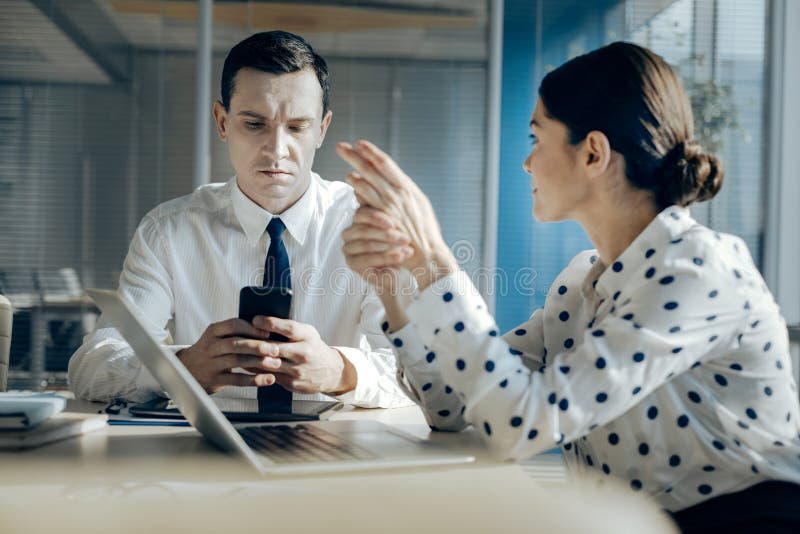 Nice Man Checking Phone while Discussing Work with Colleague Stock ...
