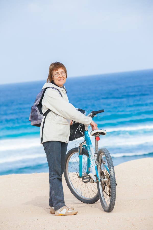 A Nice Senior Lady Riding a Bike on the Beach. Stock Image - Image of ...