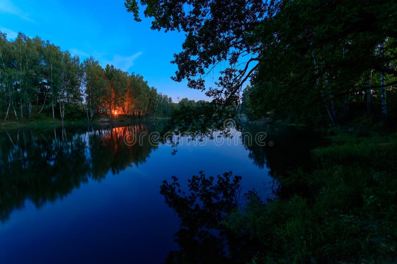 Night Landscape with Bonfire Reflection on Water Surface, Blue Sky ...