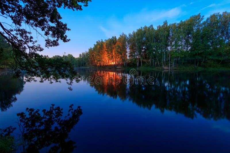 Night Landscape with Bonfire Reflection on Water Surface, Blue Sky ...