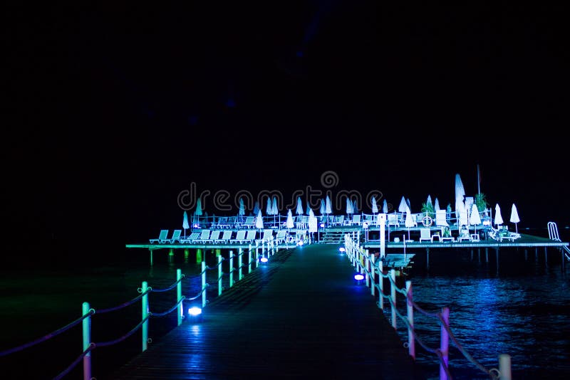 Night Pier with Sun Loungers, in Bright Lights, on the Sea Stock Image ...