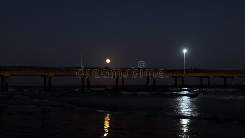 Night Scene of Ocean Pier with Reflection of Moon and a Light in the ...