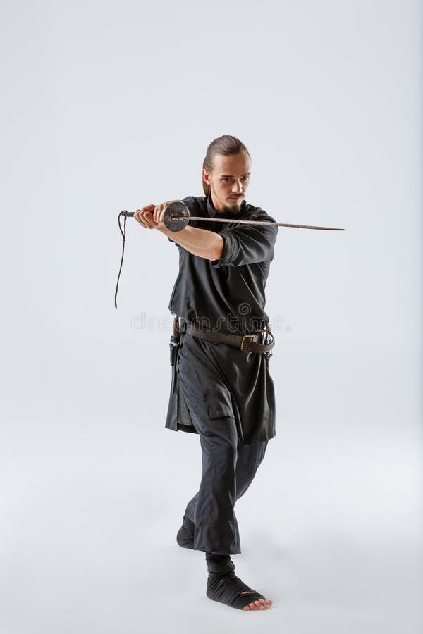 A Ninja Man Stands in a Fighting Stance with a Sword on a Gray ...