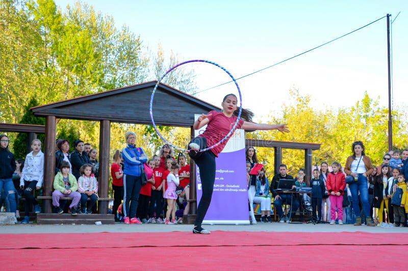 Graceful Gymnast: Young Girl Twirling Hoop Around Leg on Open Stage for ...