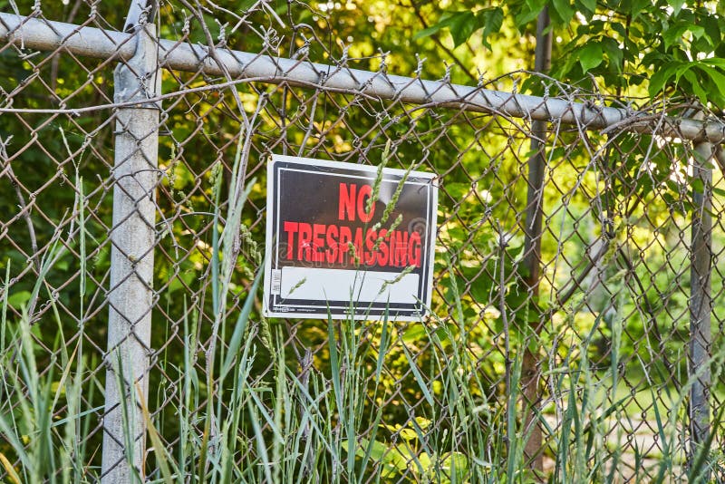 No Trespassing Sign in Red Text on Metal Fence in Forest Stock Photo ...