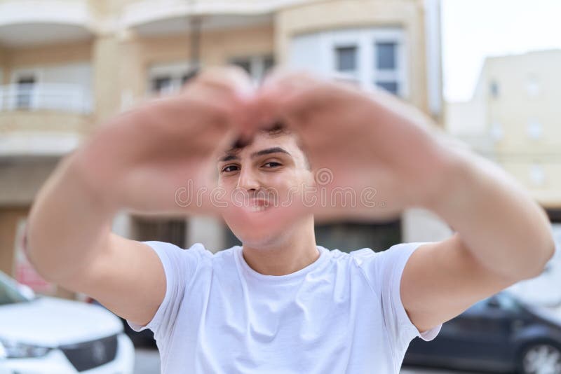 Non Binary Man Smiling Confident Doing Heart Gesture with Hands at ...