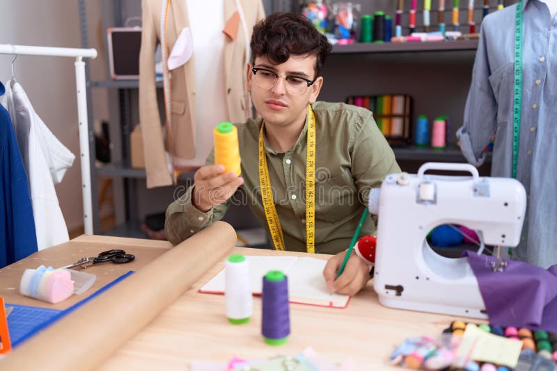 Non Binary Man Tailor Writing on Notebook Holding Thread at Atelier ...