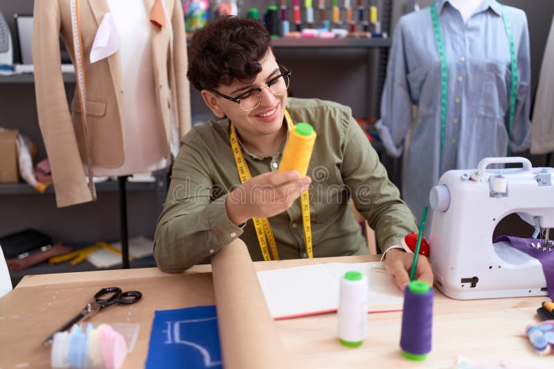 Non Binary Man Tailor Writing on Notebook Holding Thread at Atelier ...