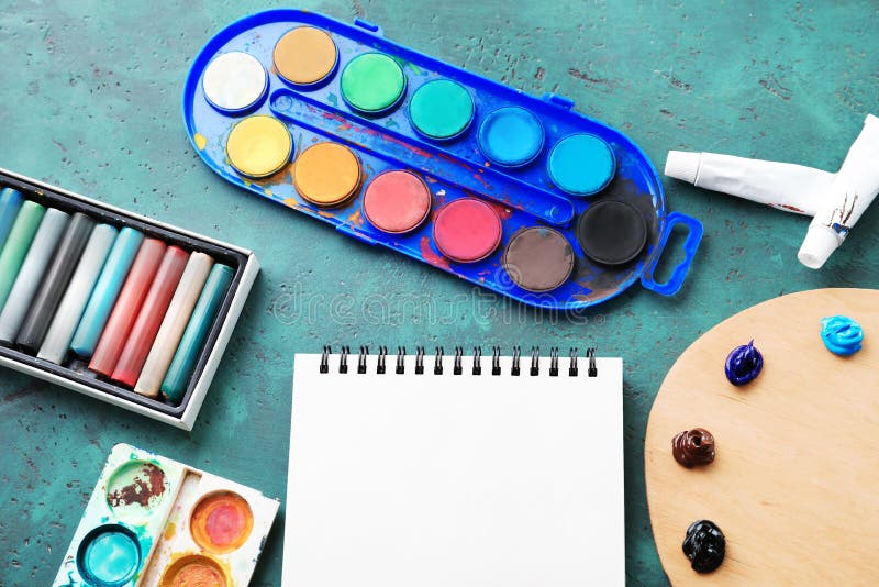 Notebook with Different Paints and Palette on Color Background Stock ...