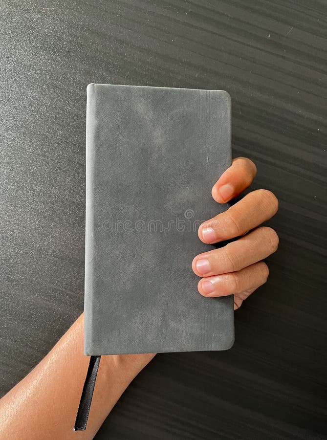 Notebook in Hand. a Small Grey Notebook To Record Everything Stock ...