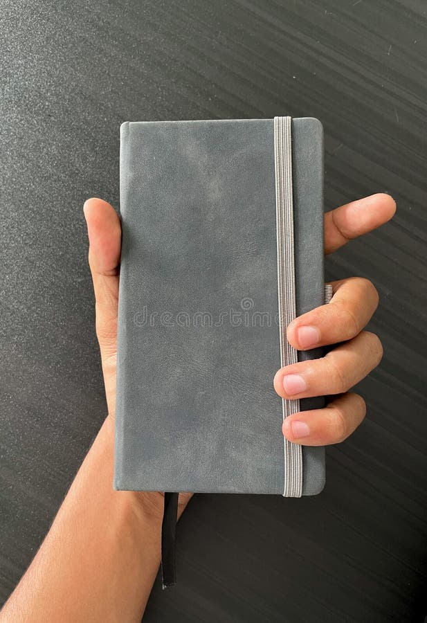 Notebook in Hand. a Small Grey Notebook To Record Everything Stock ...