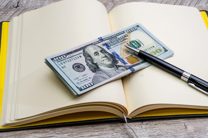 Open Notebook, Pen and Dollars on a Wooden Table Stock Image - Image of ...