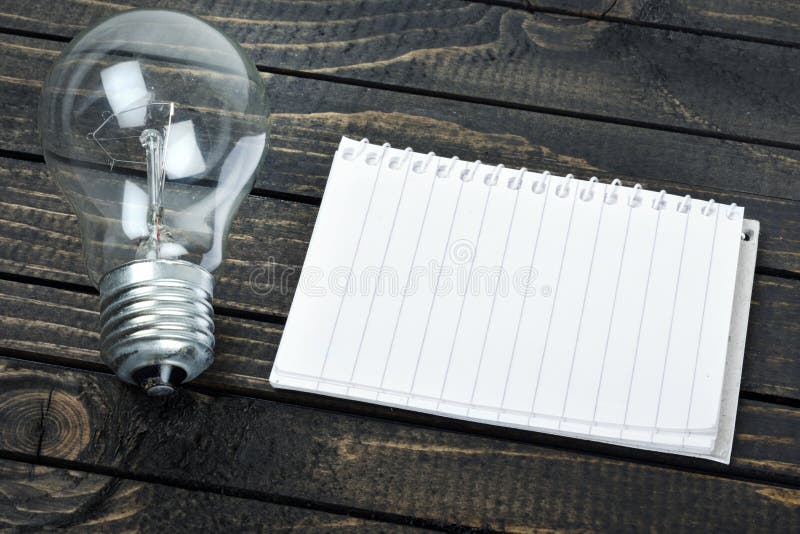Notepad and bulb on table stock image. Image of page - 76079157