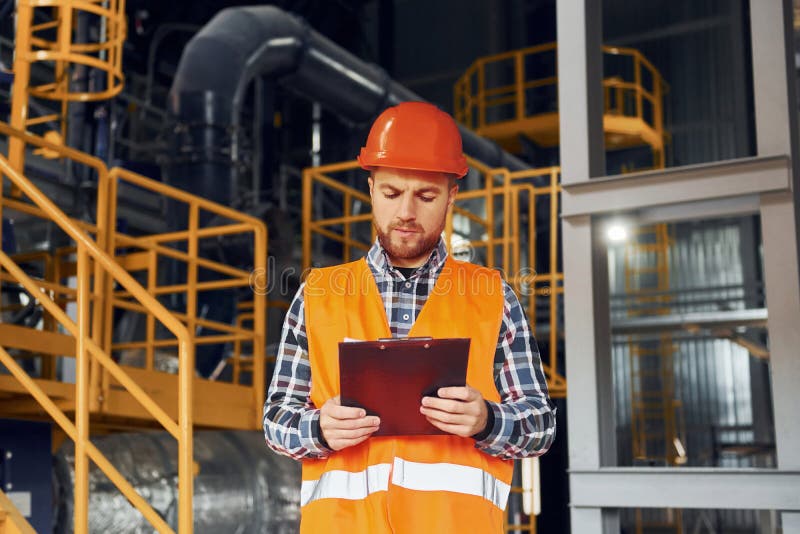 With Notepad. Construction Worker in Uniform is in the Factory Stock ...