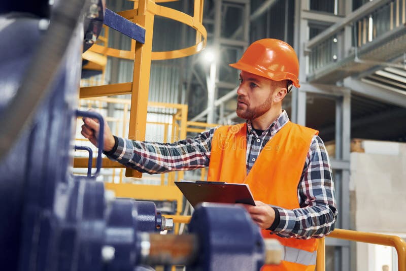 With Notepad. Construction Worker in Uniform is in the Factory Stock ...