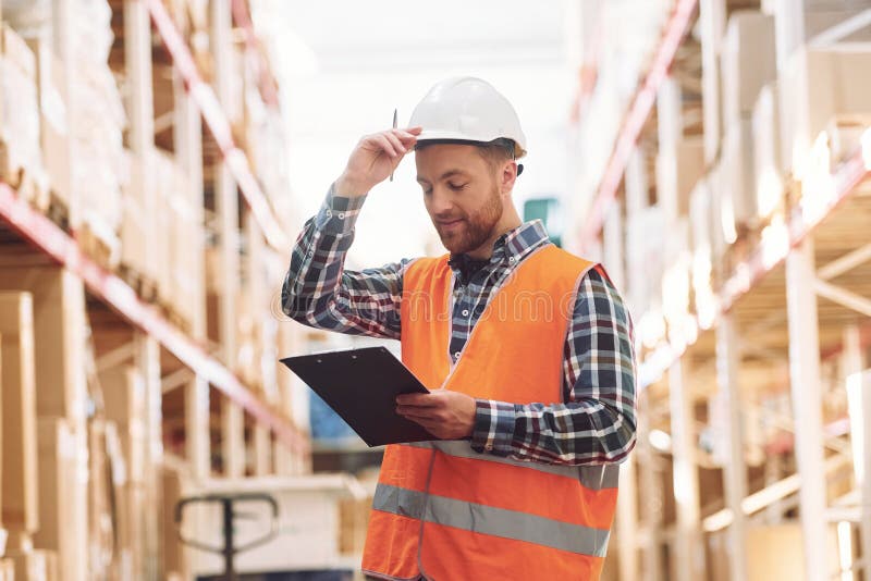 With Notepad. Employee in Uniform is Working in the Storage at Daytime ...