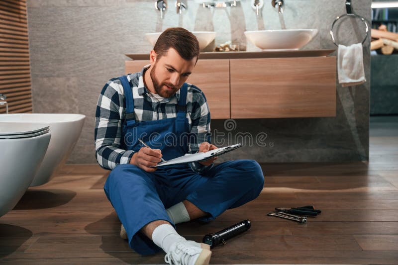 With Notepad in Hands. Plumber in Blue Uniform is at Work in the ...