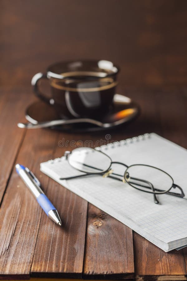 Notepad with Pen and Glasses Do Not Lie Wooden Table, and Next To a Cup ...