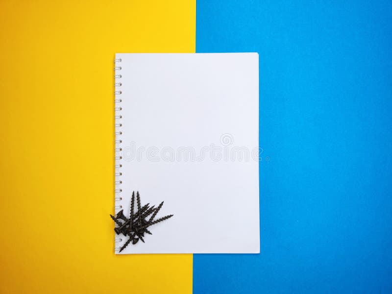 Notepad with Screws in the Lower Left Corner on a Yellow and Blue ...