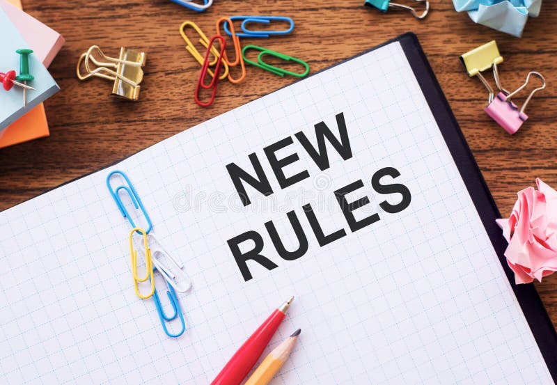 Notepad with the Text NEW RULES on the Table with Colored Paper Clips ...