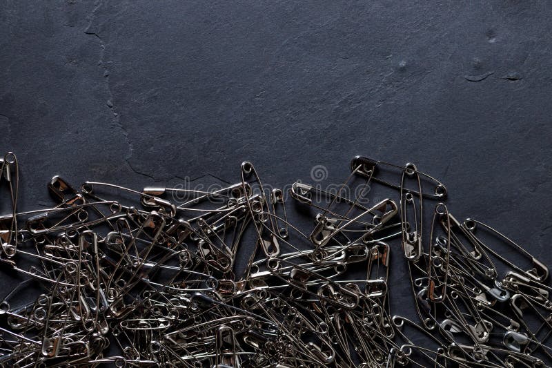A Number of Stainless Safety Pins on Black Stone Background Stock Photo ...