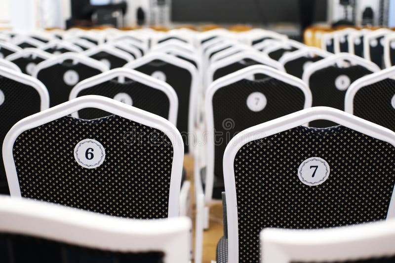 Numbered Chairs Stand in a Row Against the Backdrop of a Large Screen ...