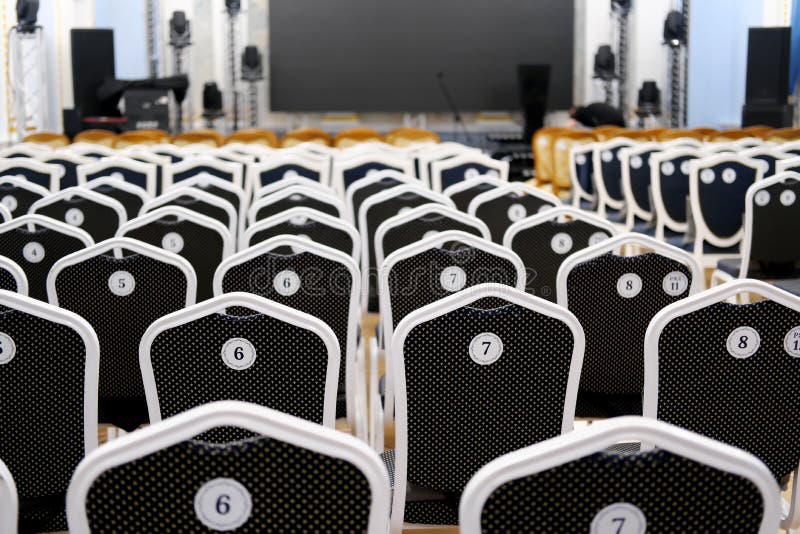 Numbered Chairs Stand in a Row Against the Backdrop of a Large Screen ...