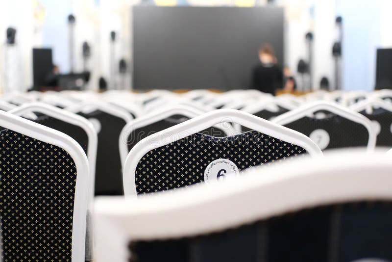 Numbered Chairs Stand in a Row Against the Backdrop of a Large Screen ...