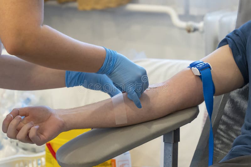 A Nurse in Blue Gloves Inserts a Needle To Take Blood. Stock Image ...