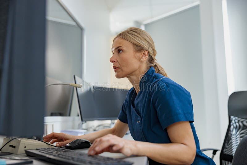Nurse on Duty Working on Computer at the Reception Desk in Modern ...