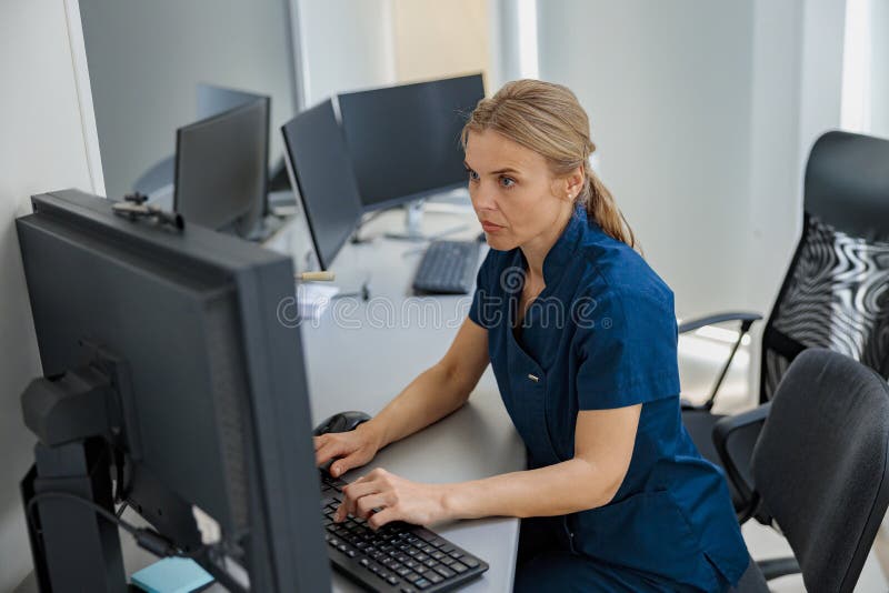Nurse on Duty Working on Computer at the Reception Desk in Modern ...