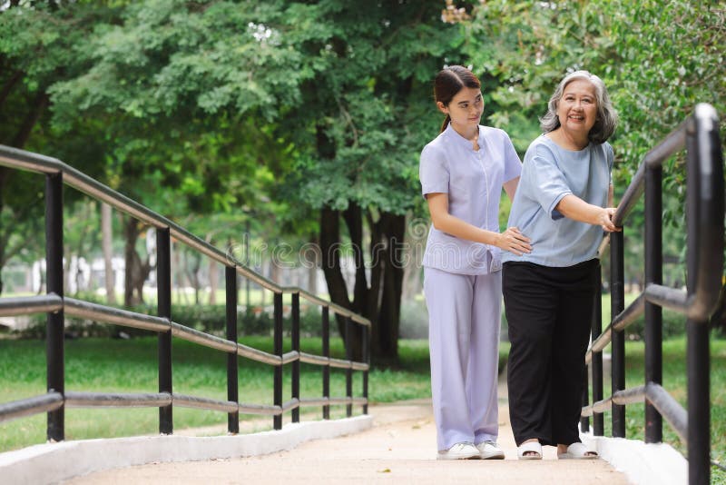A Nurse Helps an Elderly Patient To Practice Walking by Holding on To ...
