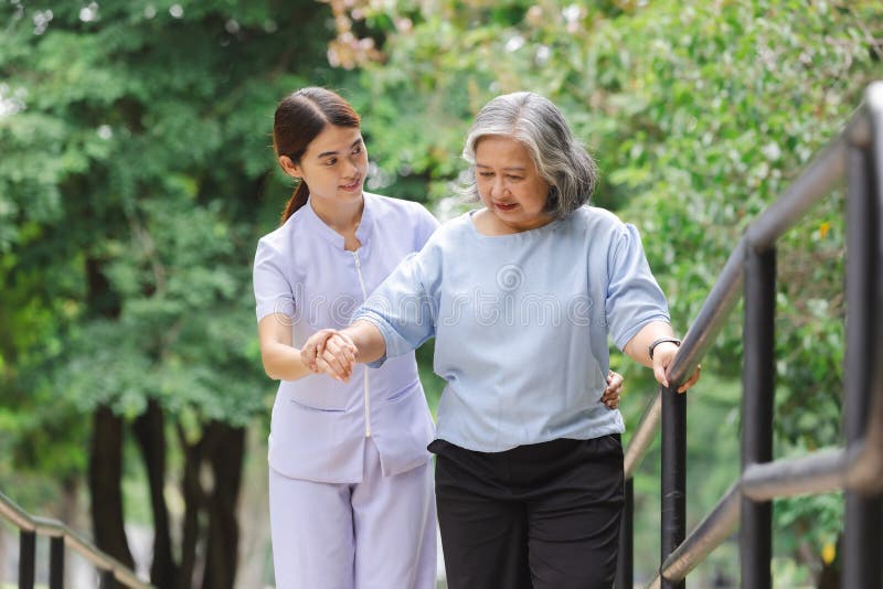 A Nurse Helps an Elderly Patient To Practice Walking by Holding on To ...